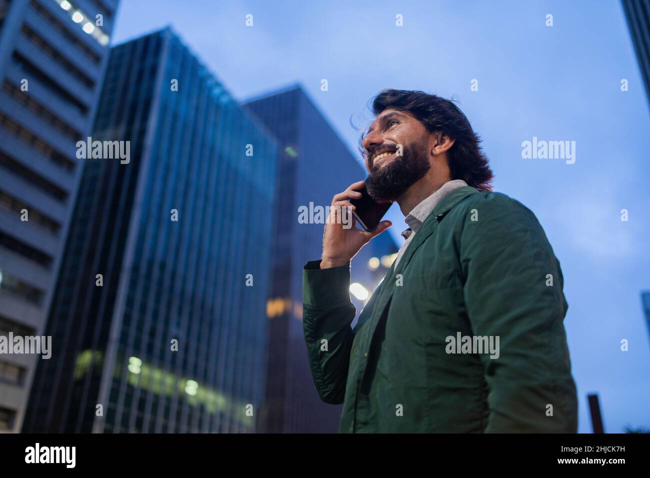 View of young man using a smartphone at night time with city view ...
