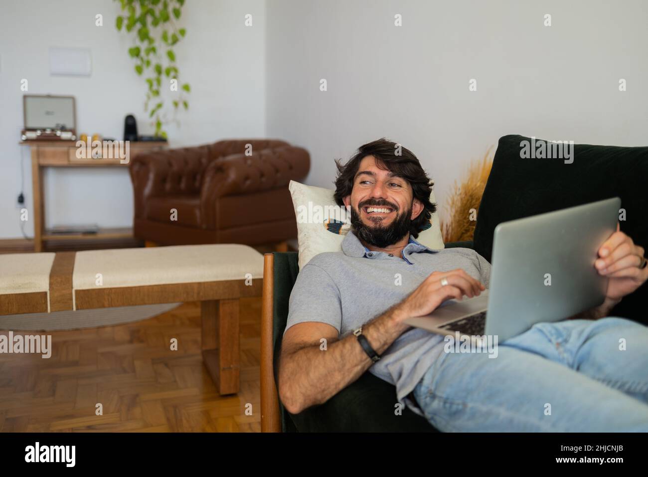 Young business man working at home from his living room couch with ...