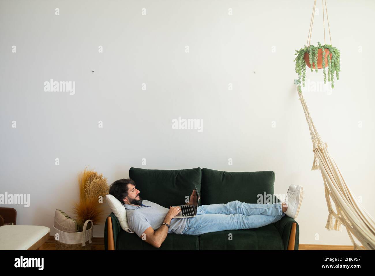 Young business man working at home from his living room couch with ...