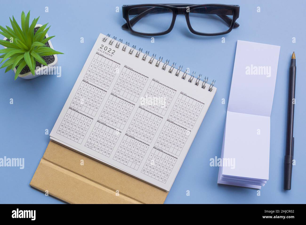 Notepad with 2022 calendar, glasses, pen and potted plant on a desk ...