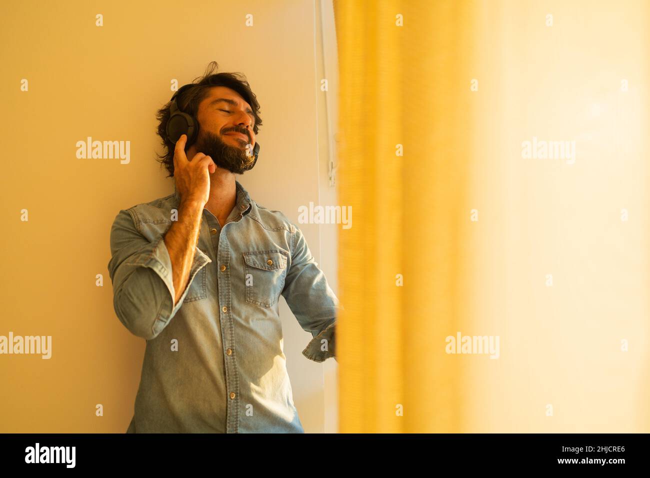 Side view of young man listening to music with headphones in his ears ...