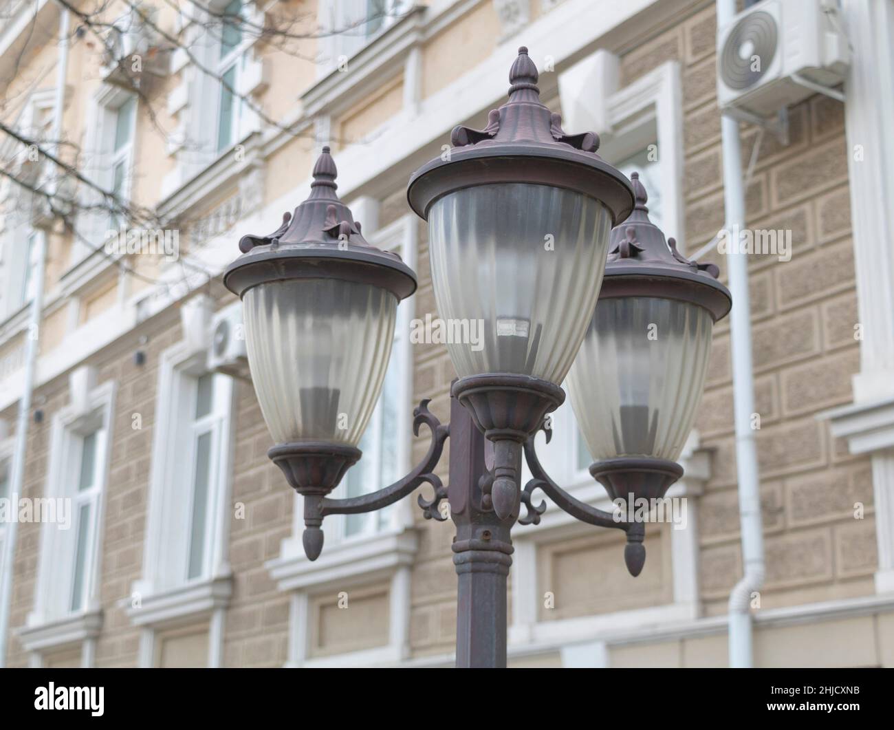 A pole with street lights off during the day with a building in the ...