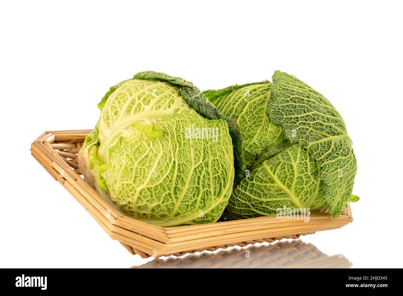 Two bales of organic Savoy cabbage in a straw dish, macro, isolated on ...