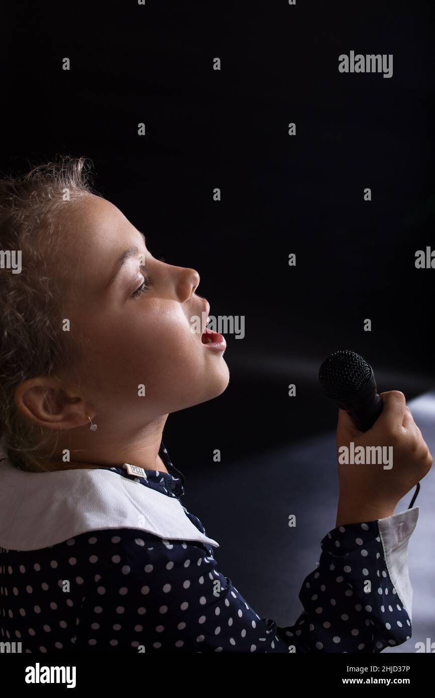 Cute little girl singing song with microphone in hand, close up on ...