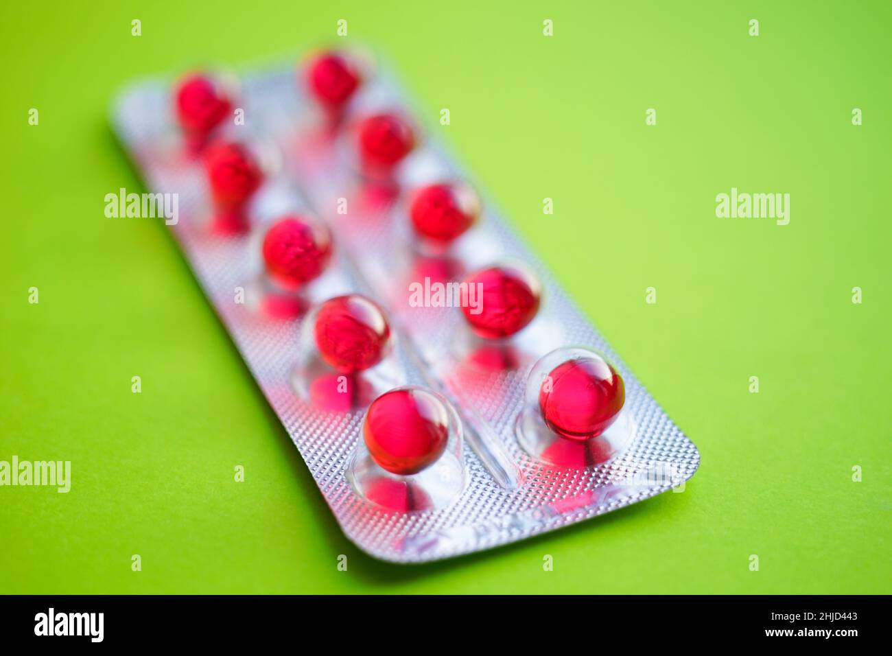 Red pills vitamins translucent capsules on a green table Stock Photo ...