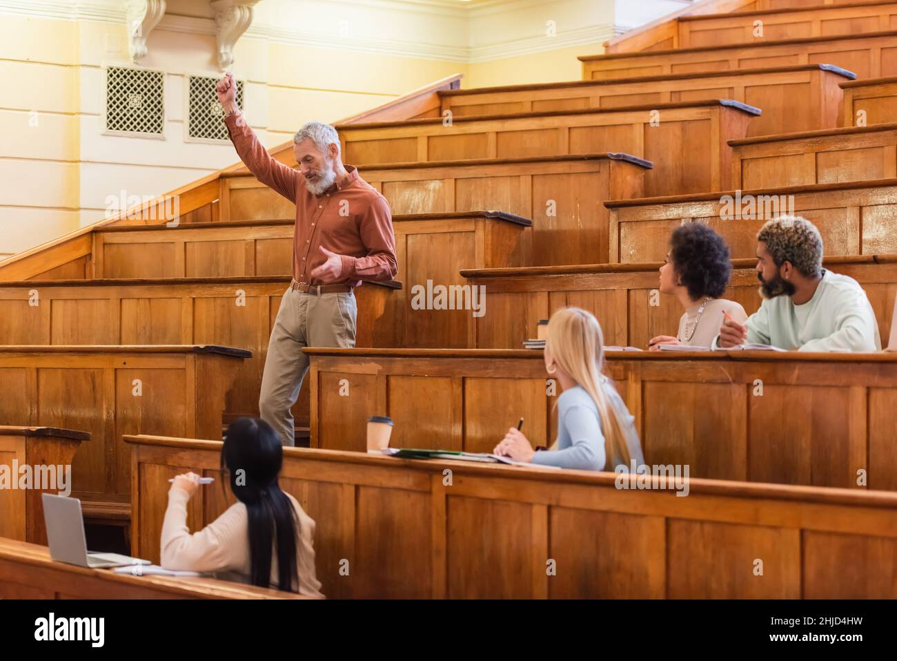 Mature professor talking during lecture near multiethnic students in ...