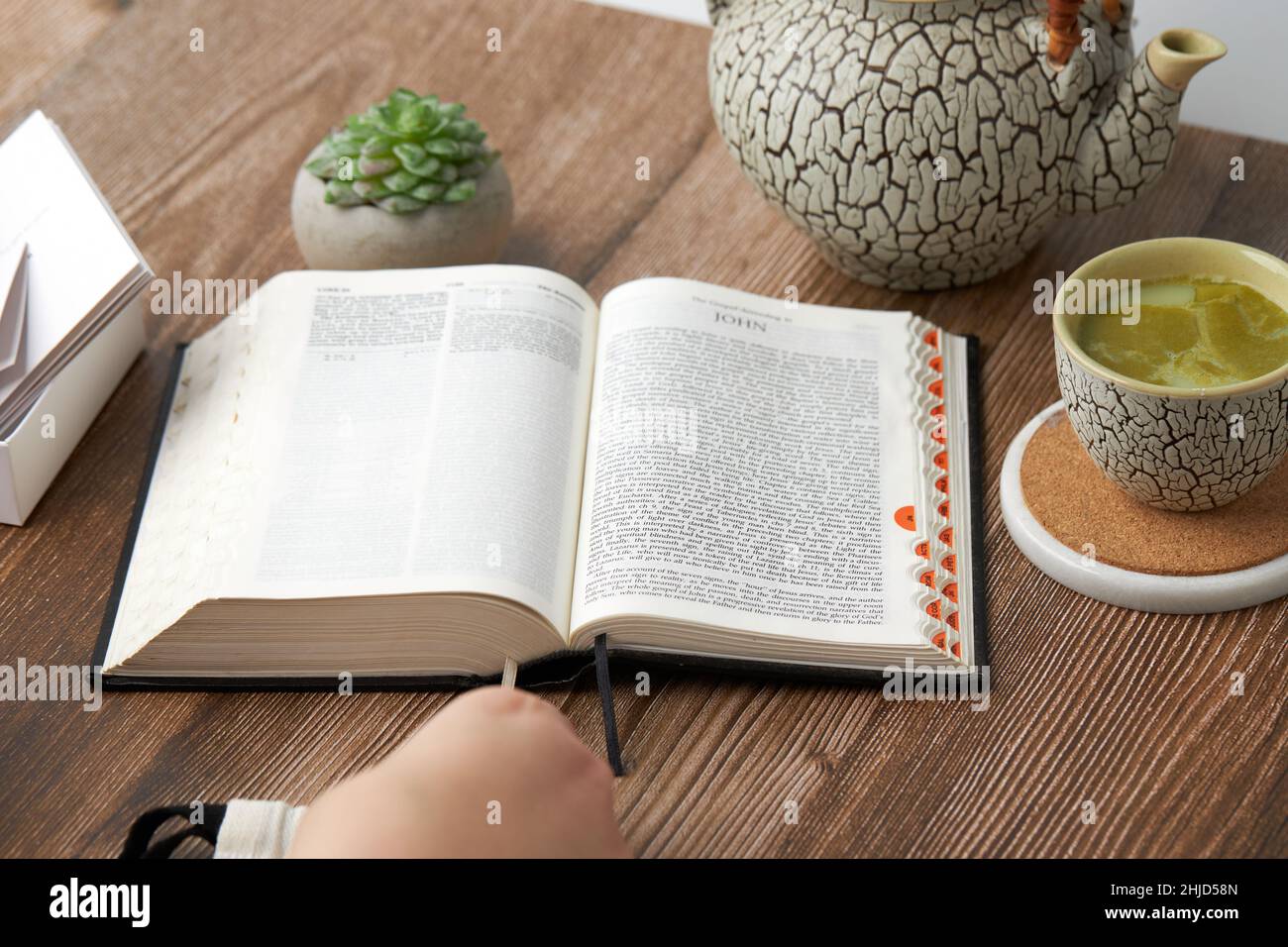 Open Holy Bible, flower pot, teapot, and a cup on the table Stock Photo ...
