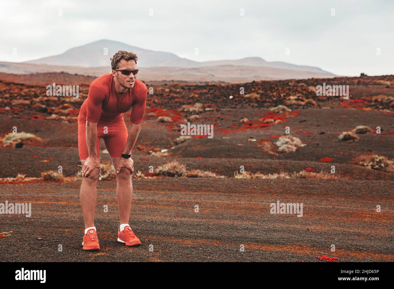 Tired sport athlete runner taking a break breathing during exercise workout on mountain trail ...