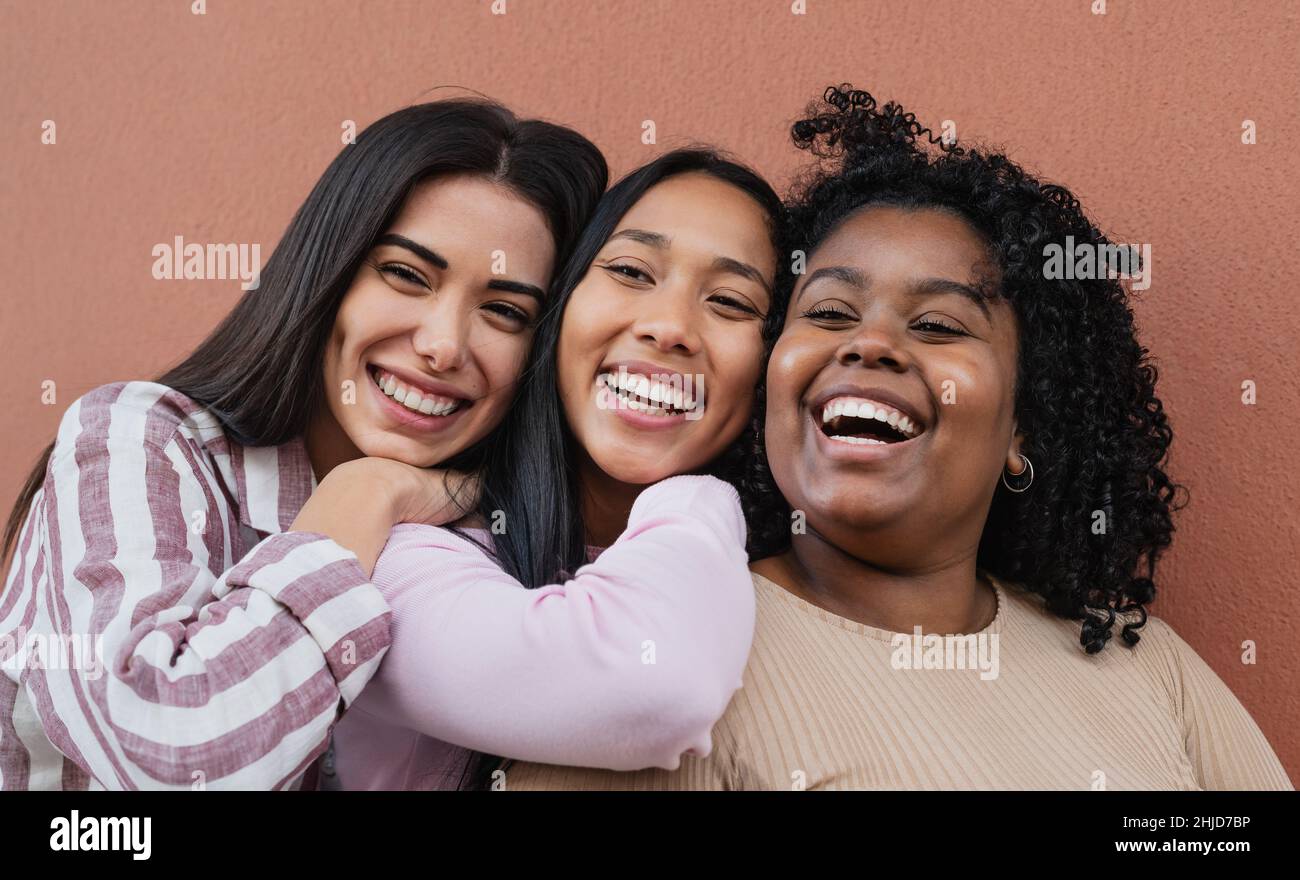 Portrait of happy multiracial friends embracing and smiling in front of ...
