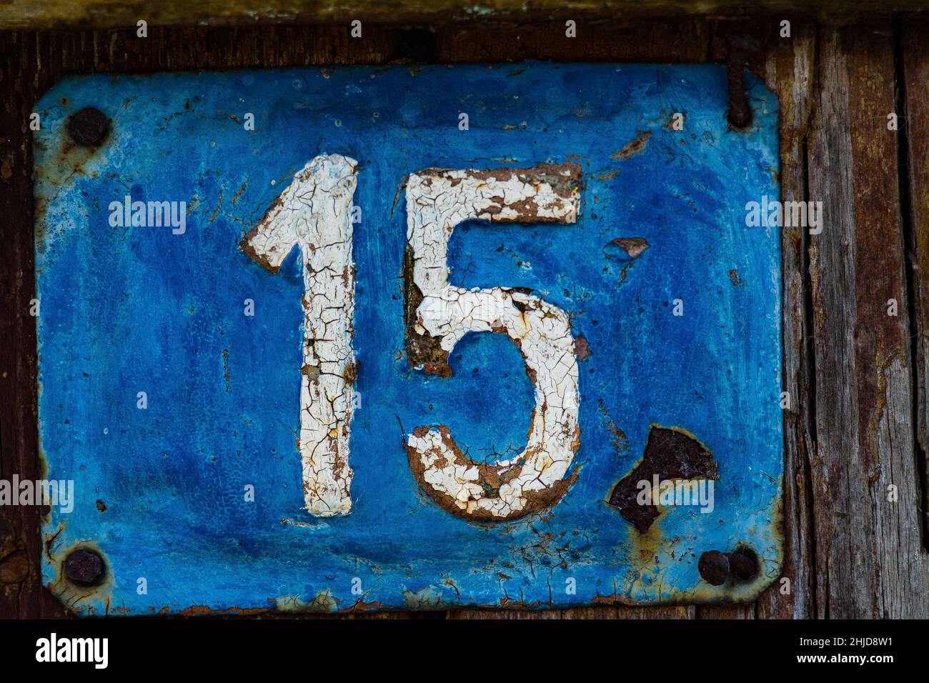 Vintage plate on the house with the number 15. Cracked blue paint and ...