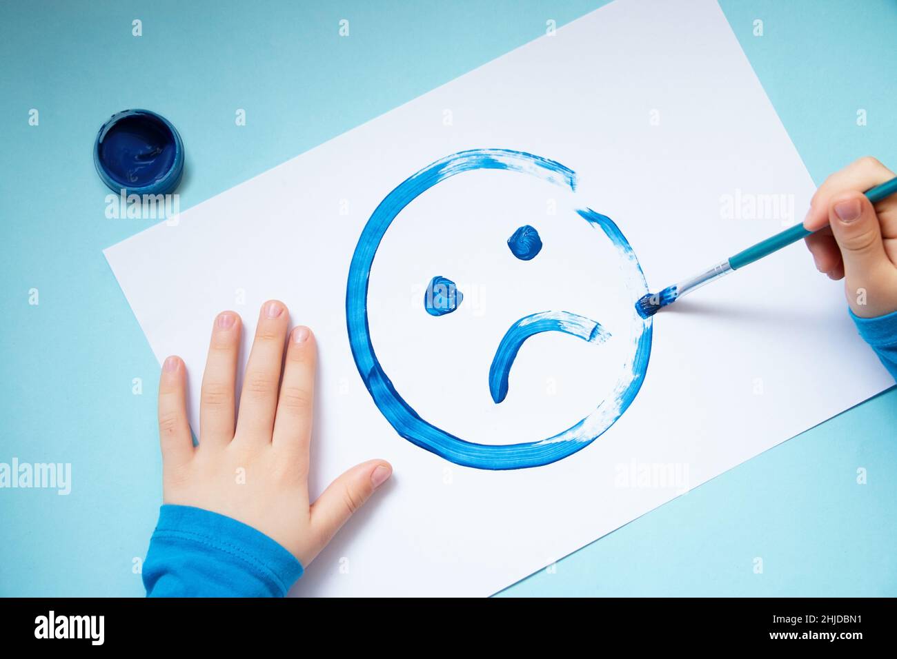 Top view of the child hands,drawing sad face.Blue monday and mental ...