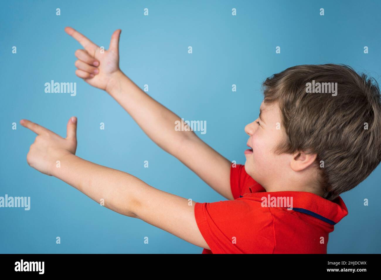 a cute Caucasian boy aggressively and cheerfully shoots his fingers ...