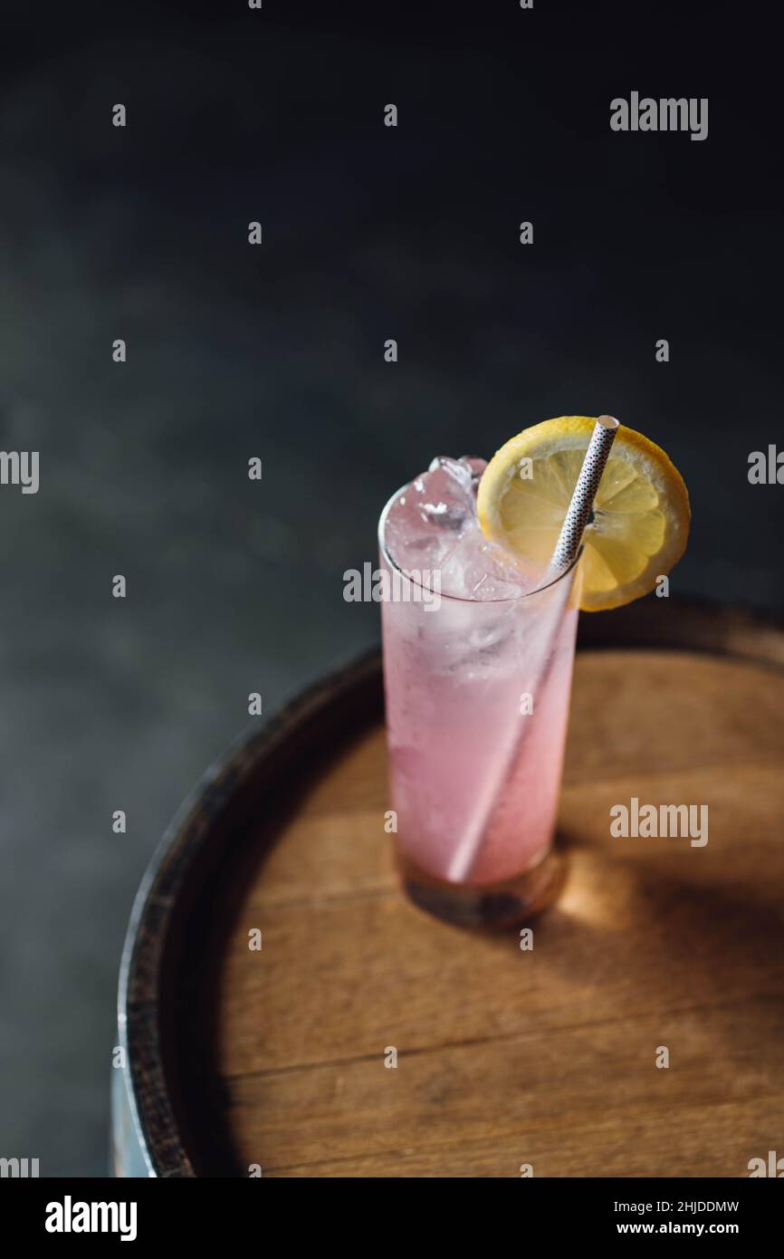 simple pink lemonade with straw and lemon wheel on whiskey barrel with ...
