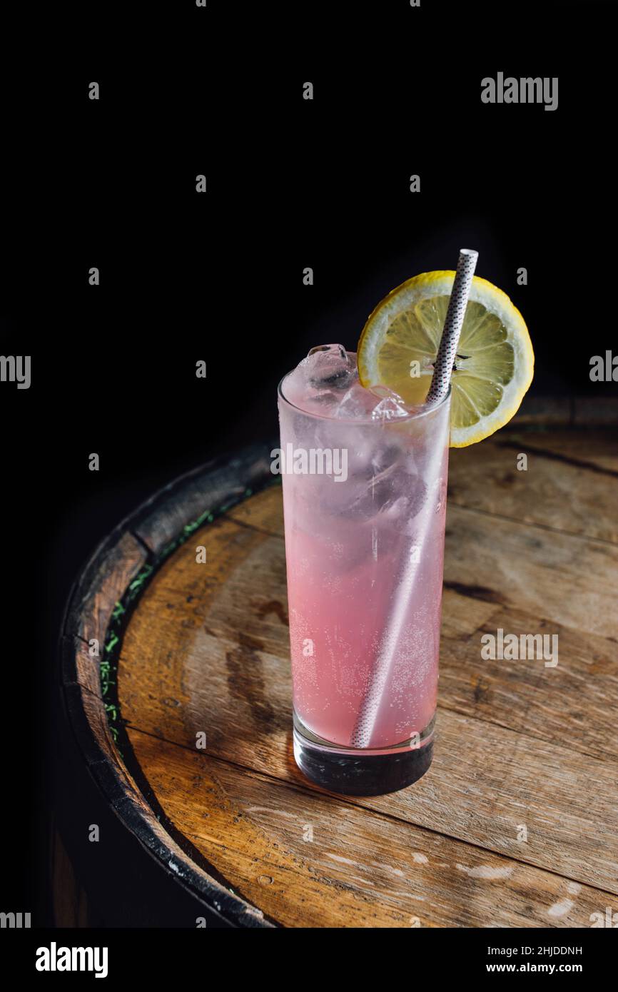simple pink lemonade with straw and lemon wheel on whiskey barrel with ...