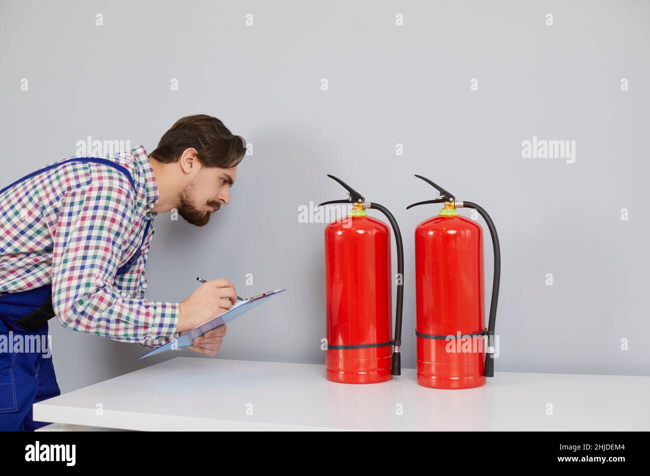 Fire safety engineer taking notes while checking fire extinguishers ...