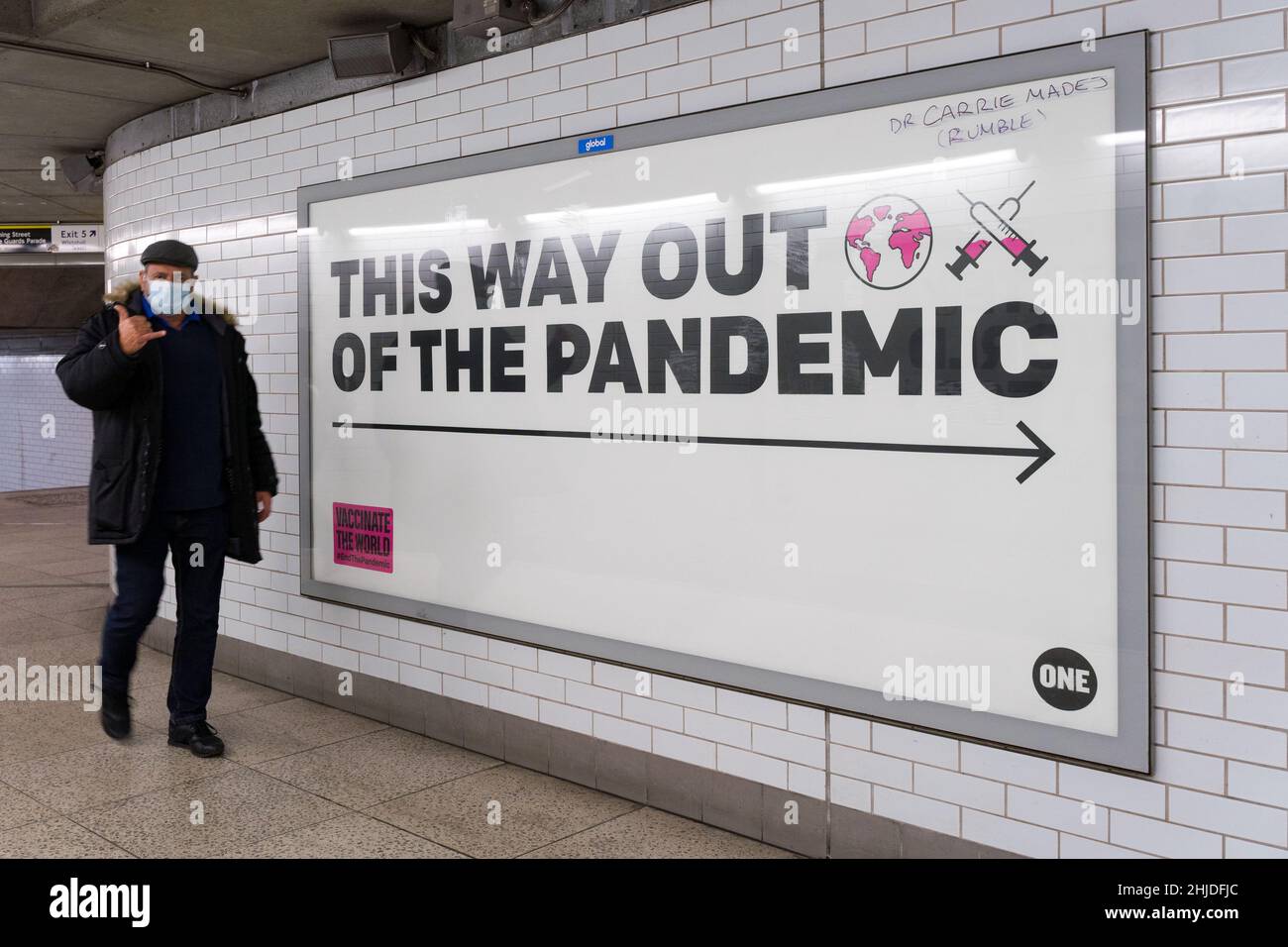 a man walk next to a poster billboard showing "This way out of the ...