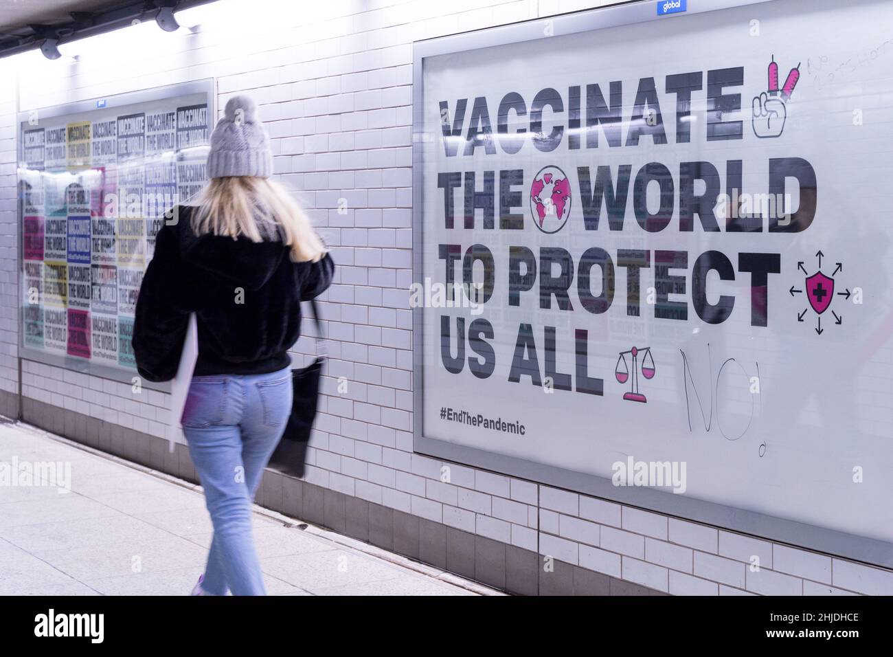 woman walk past a huge poster on the billboard showing "vaccine the ...