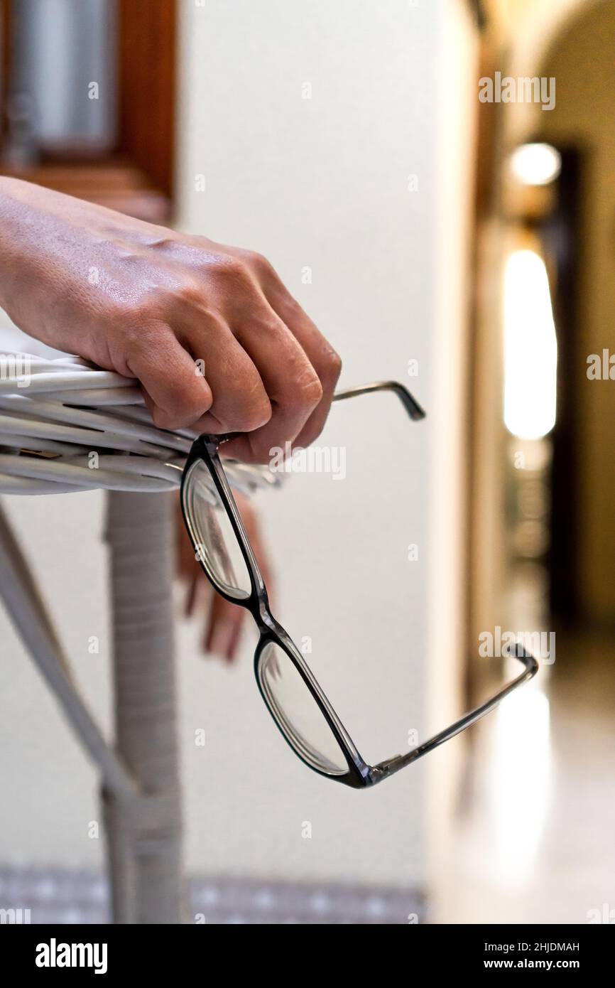 Tired person resting on a table and holding glasses after work at home ...
