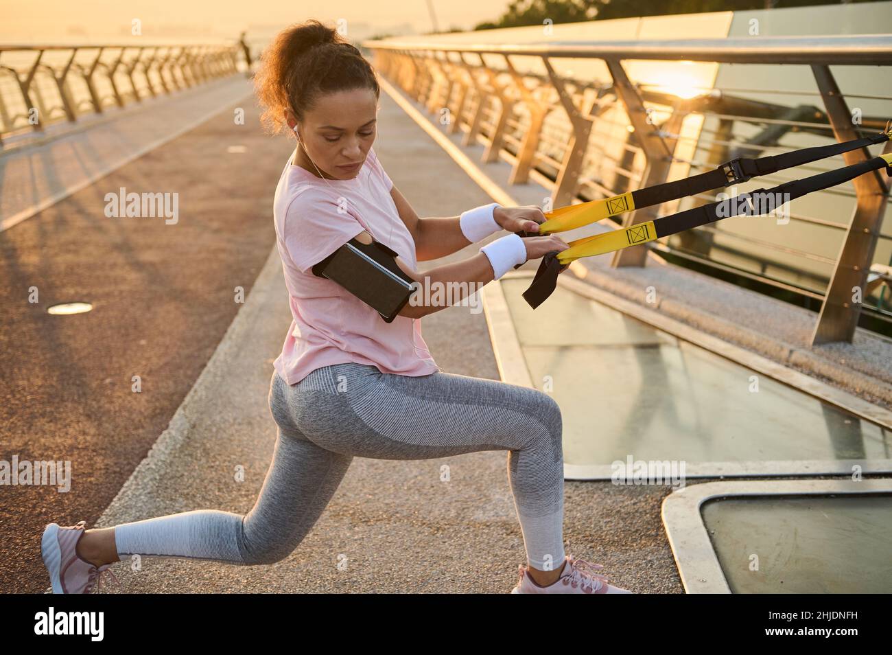 Athletic sportswoman exercises with suspension straps during body ...