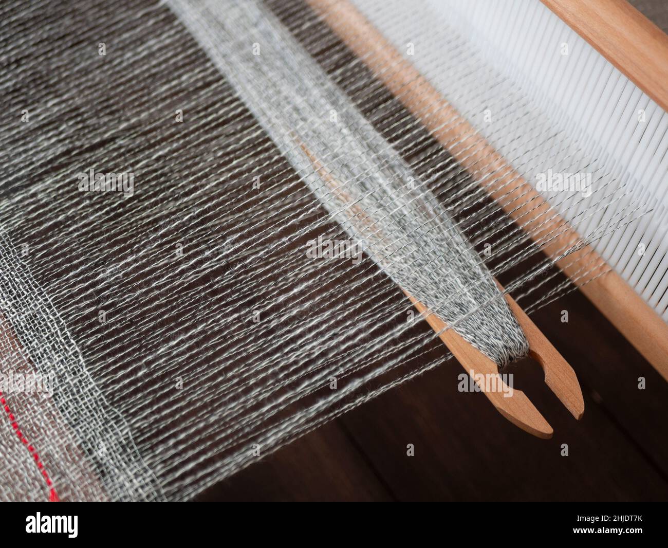 Shuttle with gray linen thread sent through shed on a loom. Weaving ...