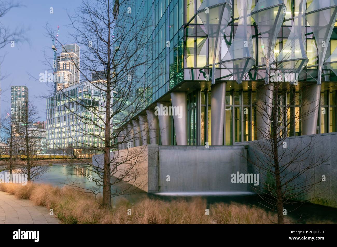 Illuminated facade of U.S Embassy in London showing moat and gardens ...