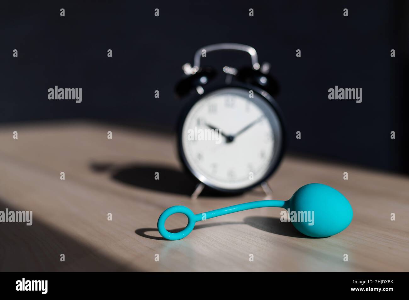 Alarm clock and vibrator on the table. Time for training intimate ...