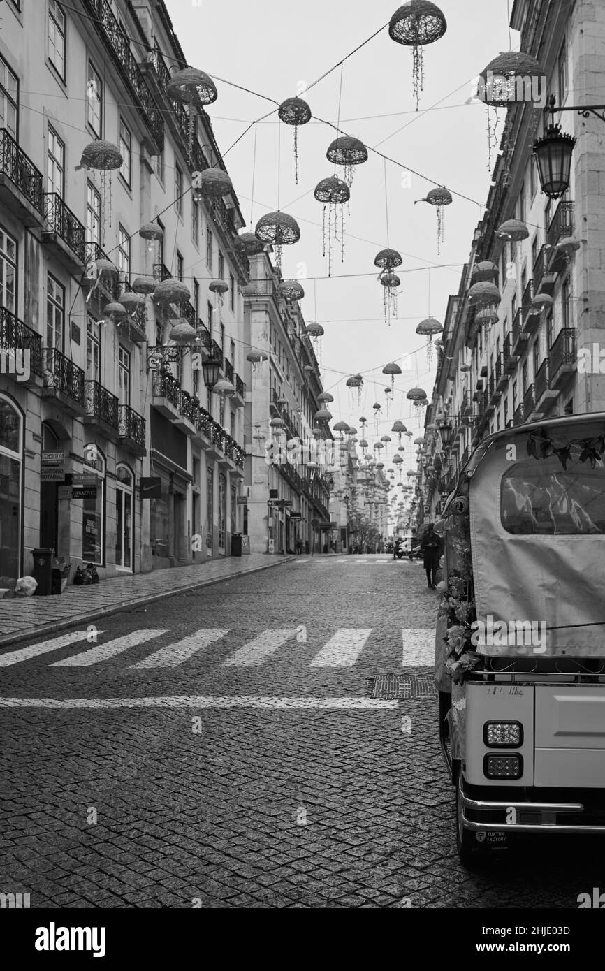 A vertical grayscale shot of a narrow street surrounded by buildings ...