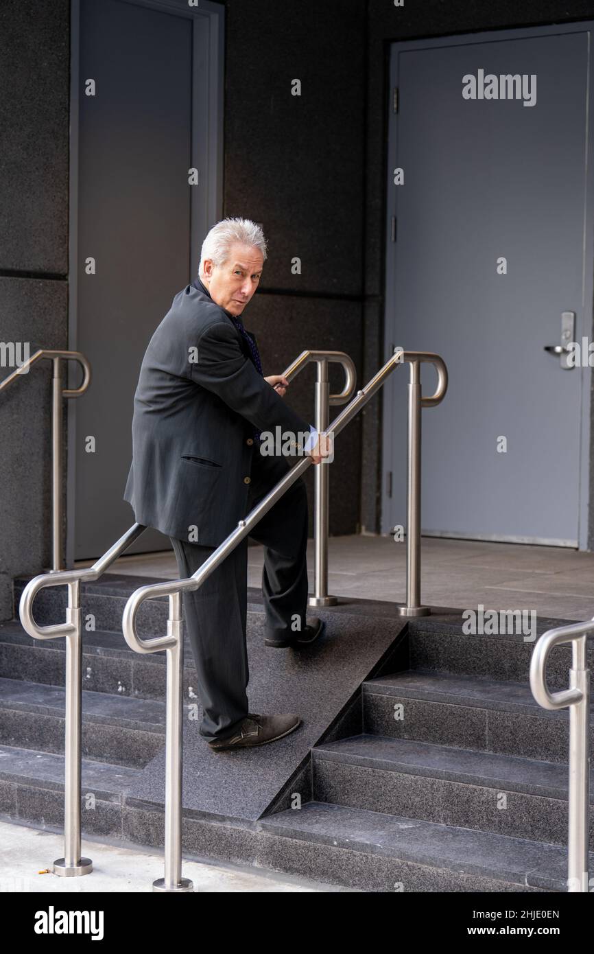 Businessman walking up a very narrow handicapped ramp to an office ...