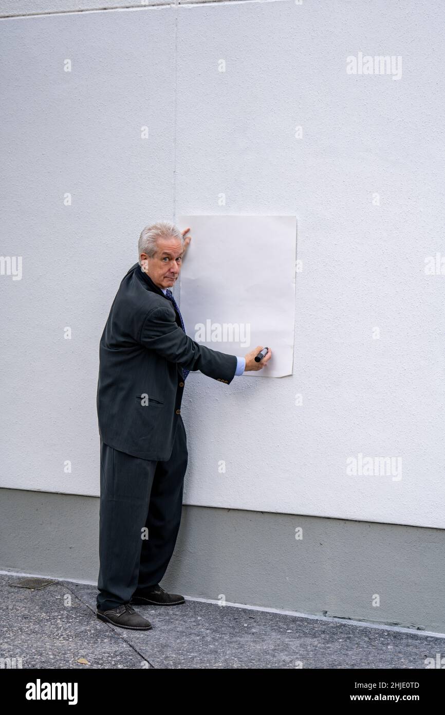 Photo of a businessman holding up a posterboard getting ready to write ...