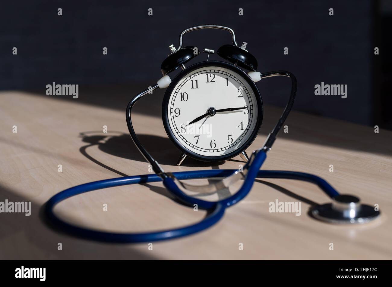 Classic old black mechanical alarm clock with stethoscope on a wooden ...