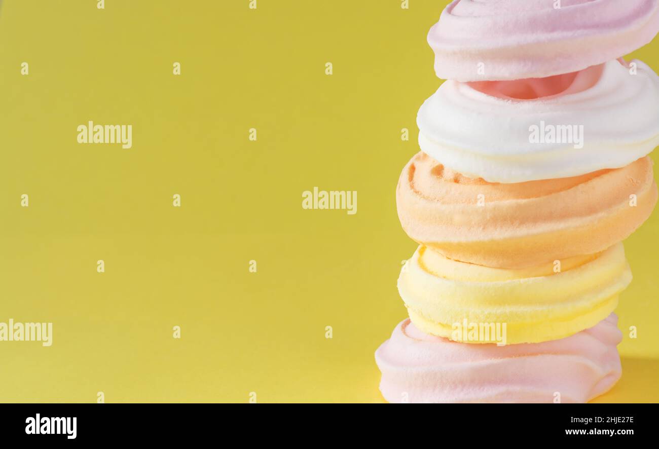 Yellow background with a stack of yellow-pink meringue, horizontal ...