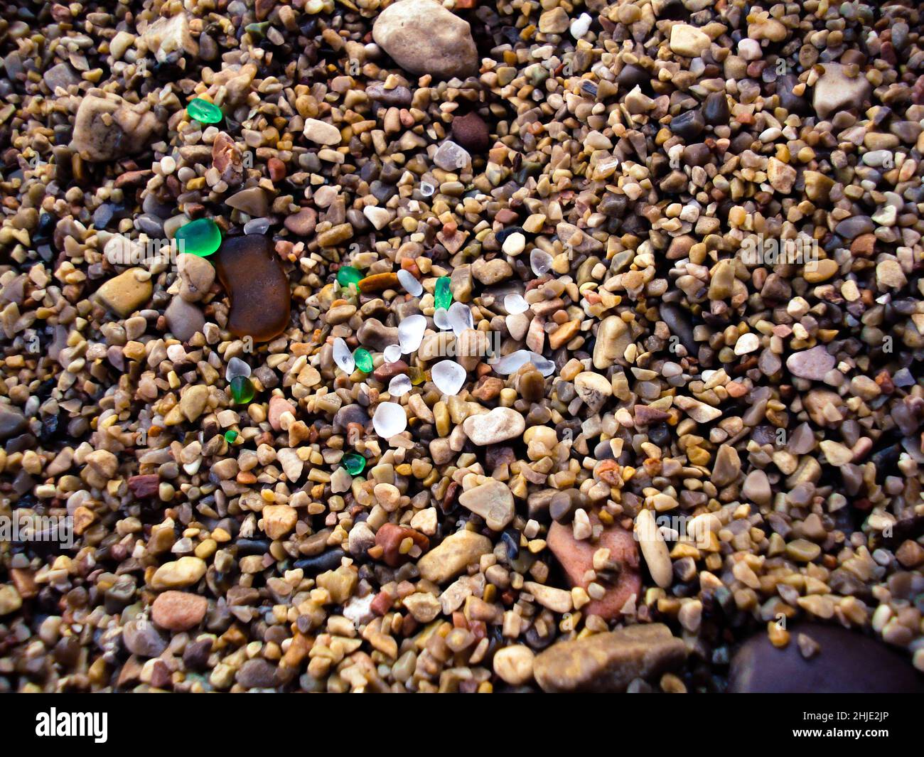 Multi-colored sea pebbles with glass pieces on the beach Stock Photo ...