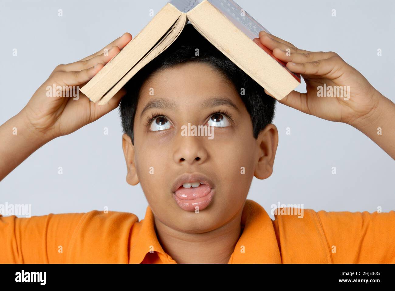 Education Concept Indian school boy student holding book on head ...