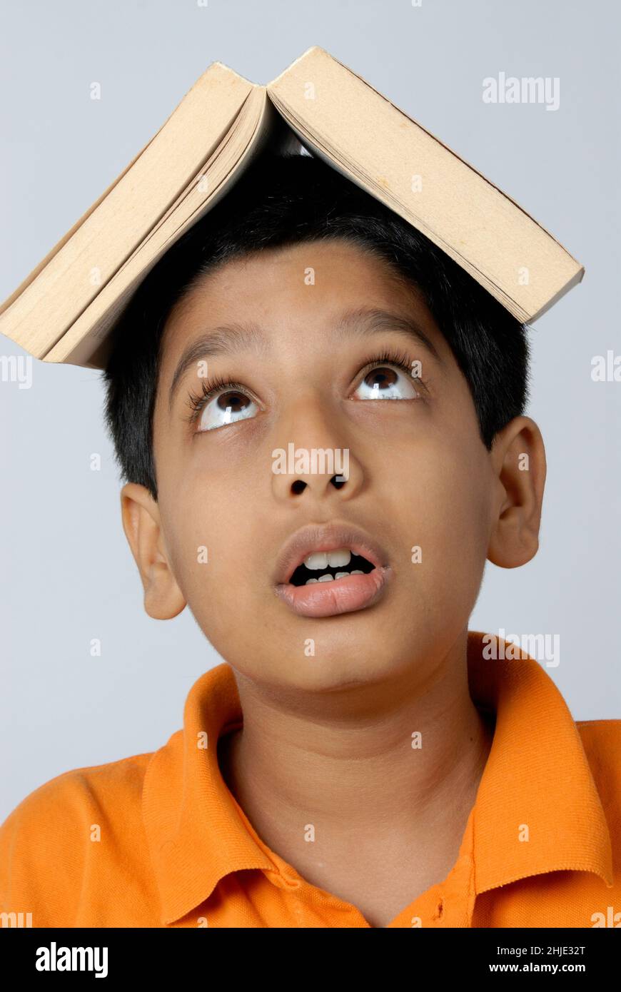 Education Concept Indian school boy student holding book on head ...