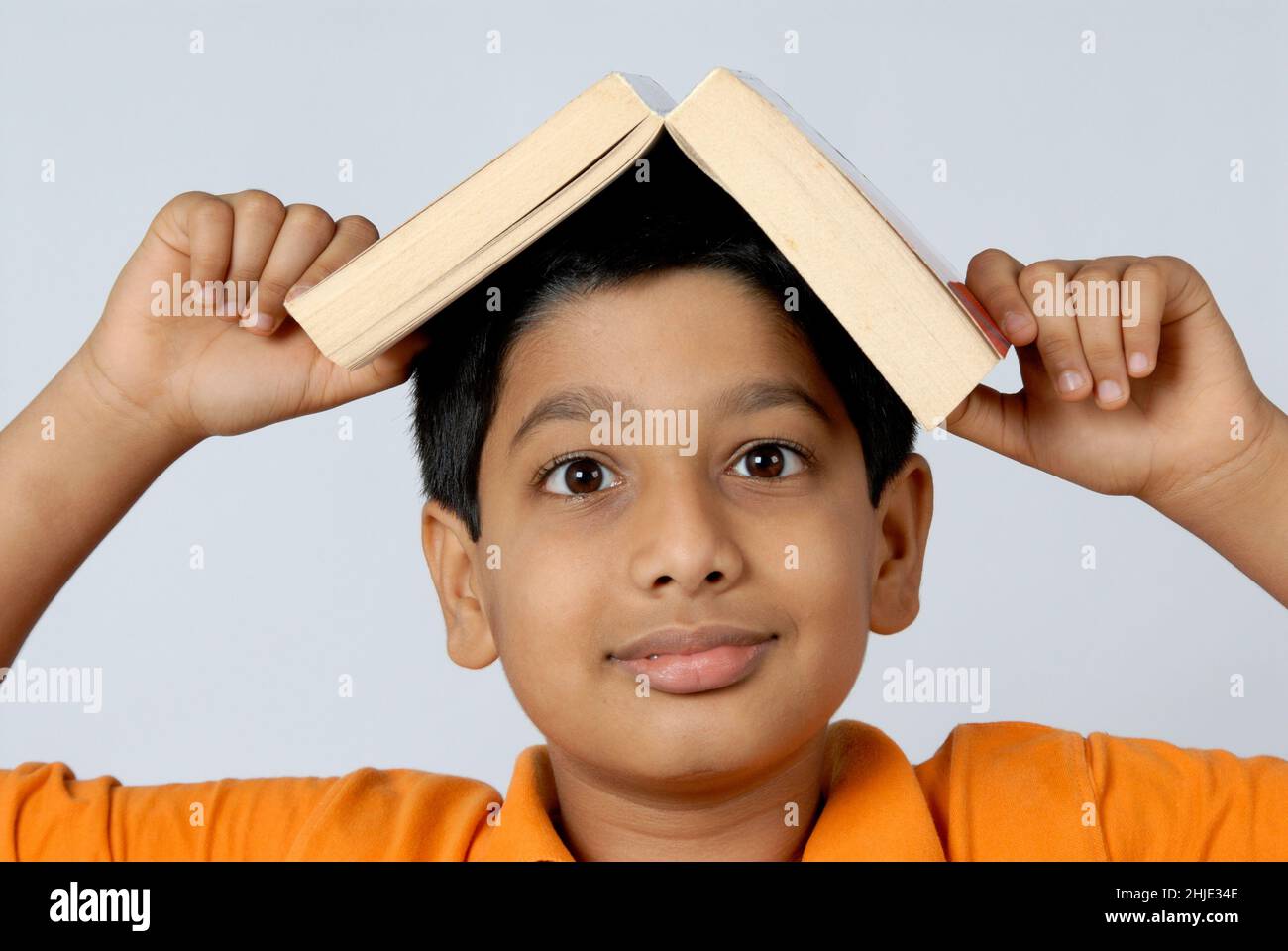 Education Concept Indian school boy student holding book on head ...