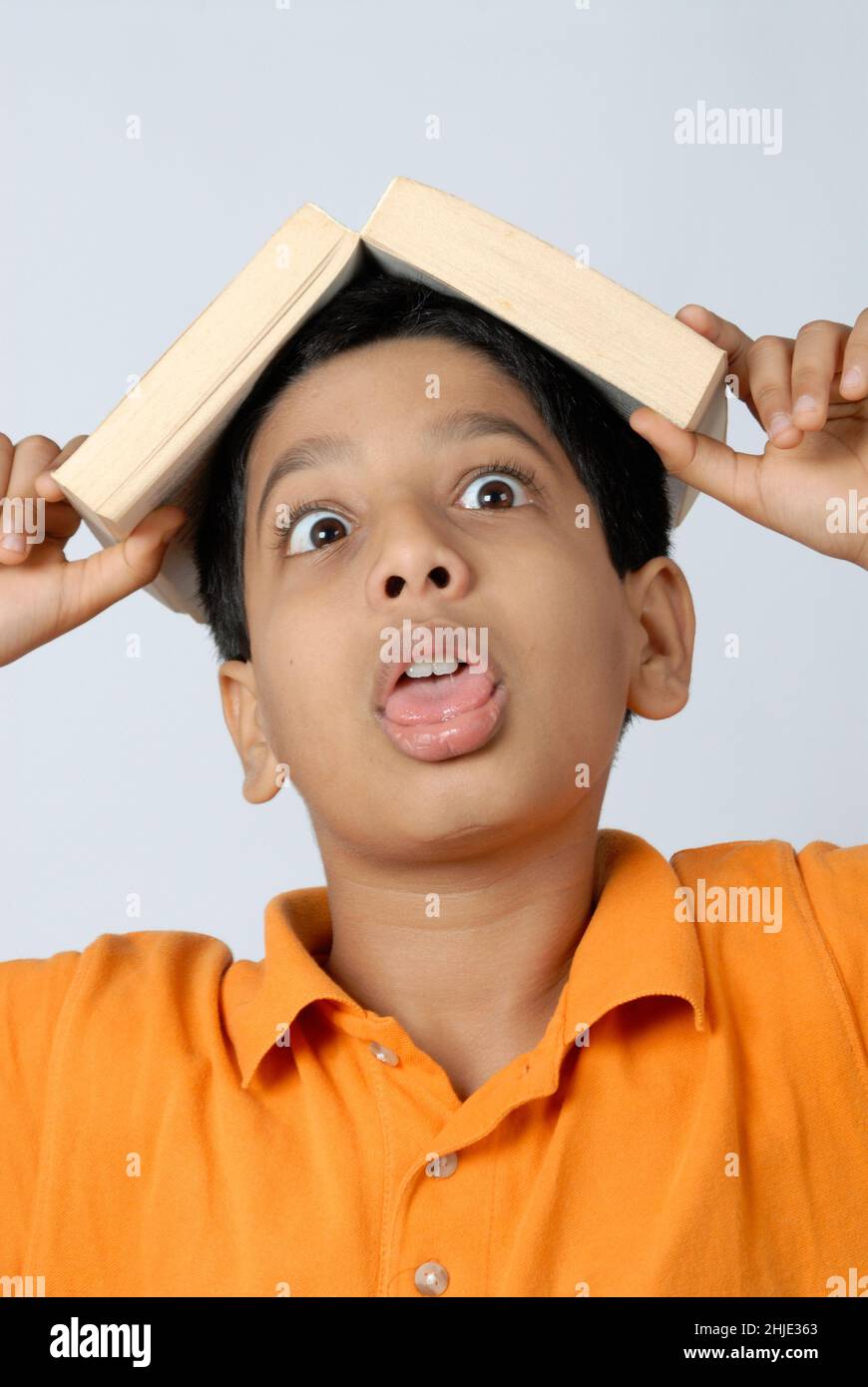 Education Concept Indian school boy student holding book on head ...