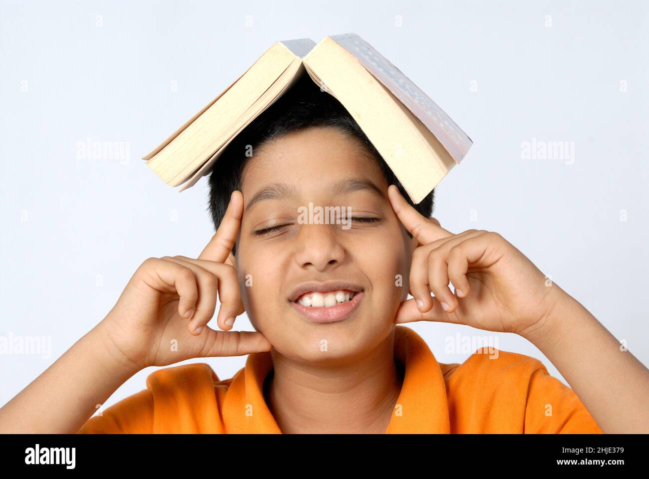 Education Concept Indian school boy student holding book on head ...