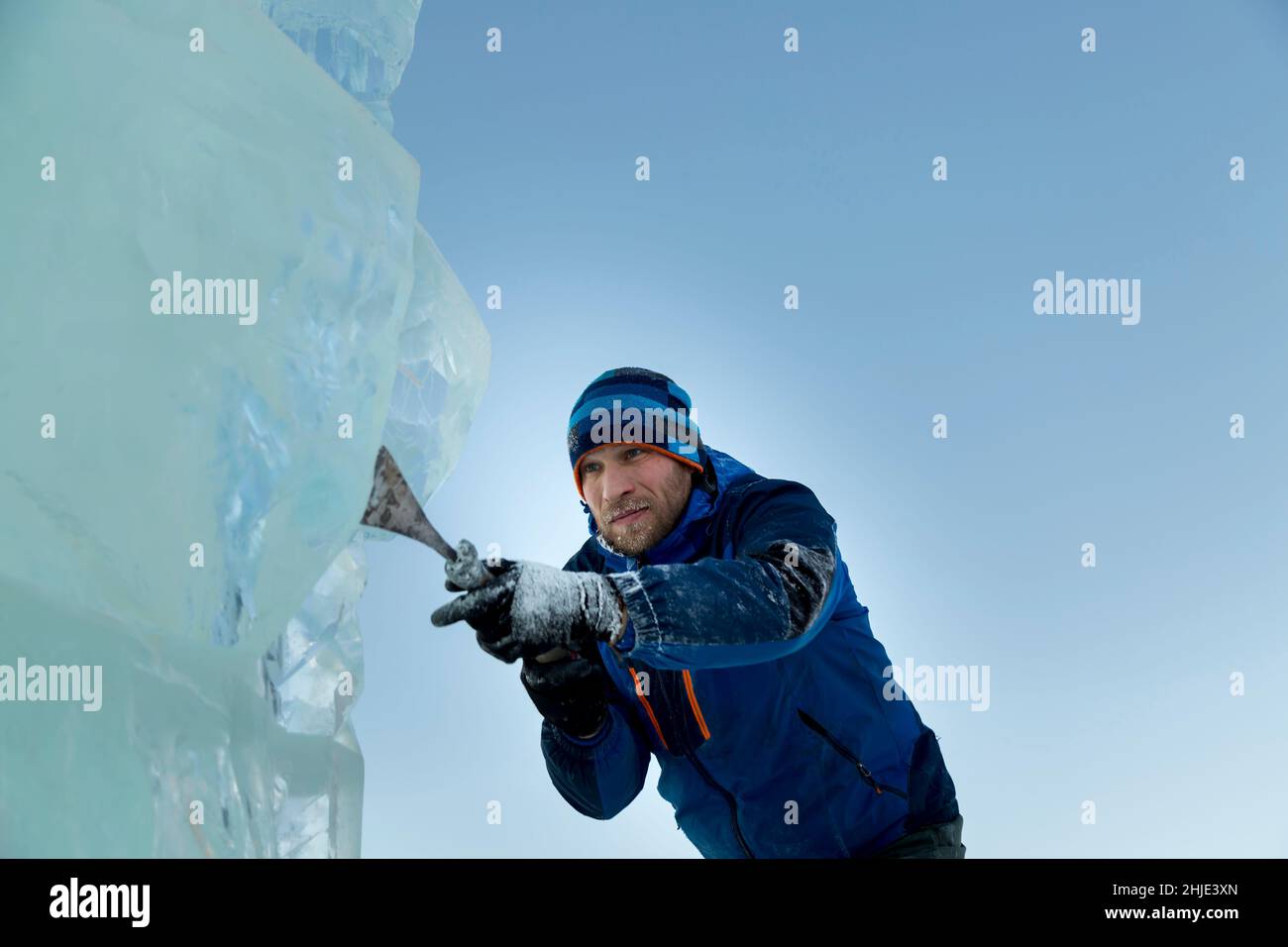 The sculptor cuts an ice figure out of ice with a chisel for Christmas ...