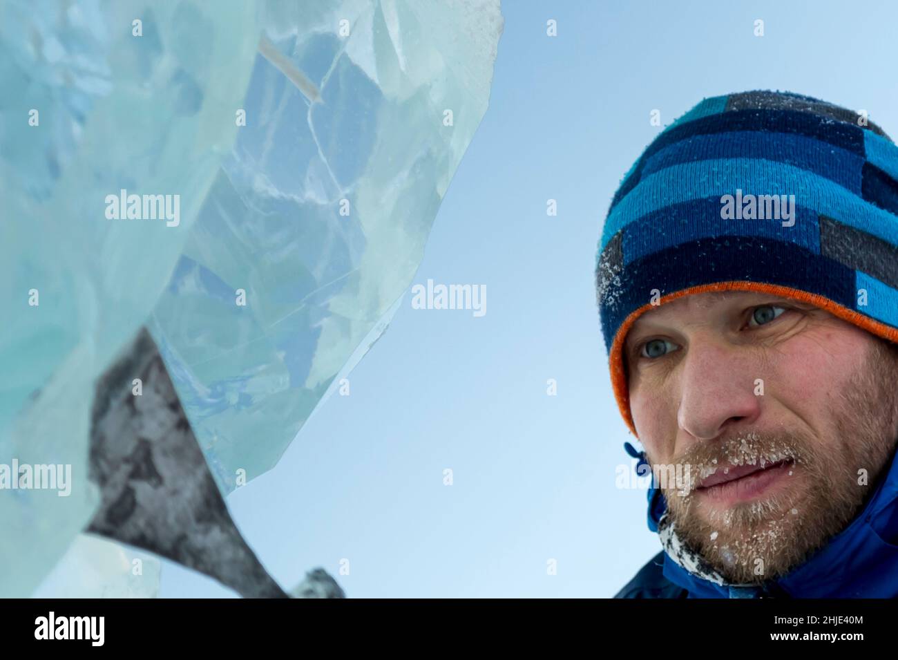 The sculptor cuts an ice figure out of ice with a chisel for Christmas ...