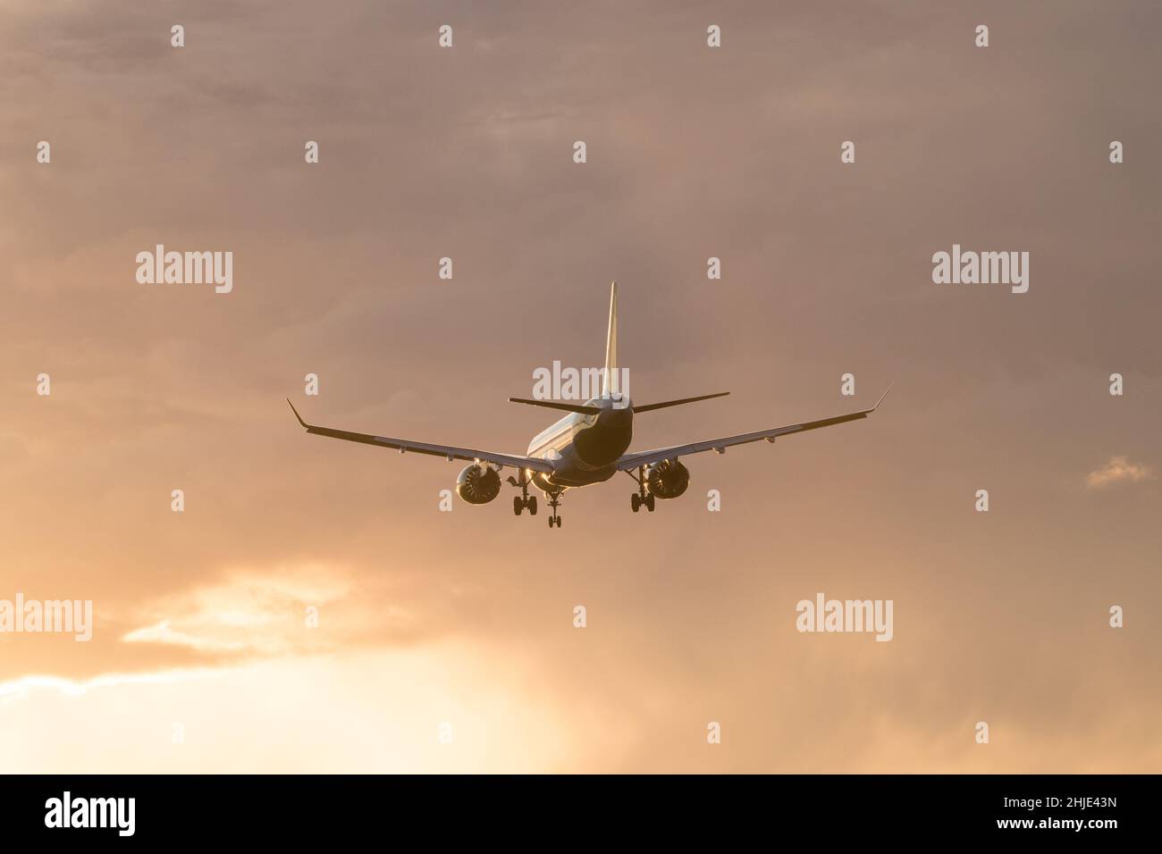 Big airplane in motion flying during the sunset through the clouds ...
