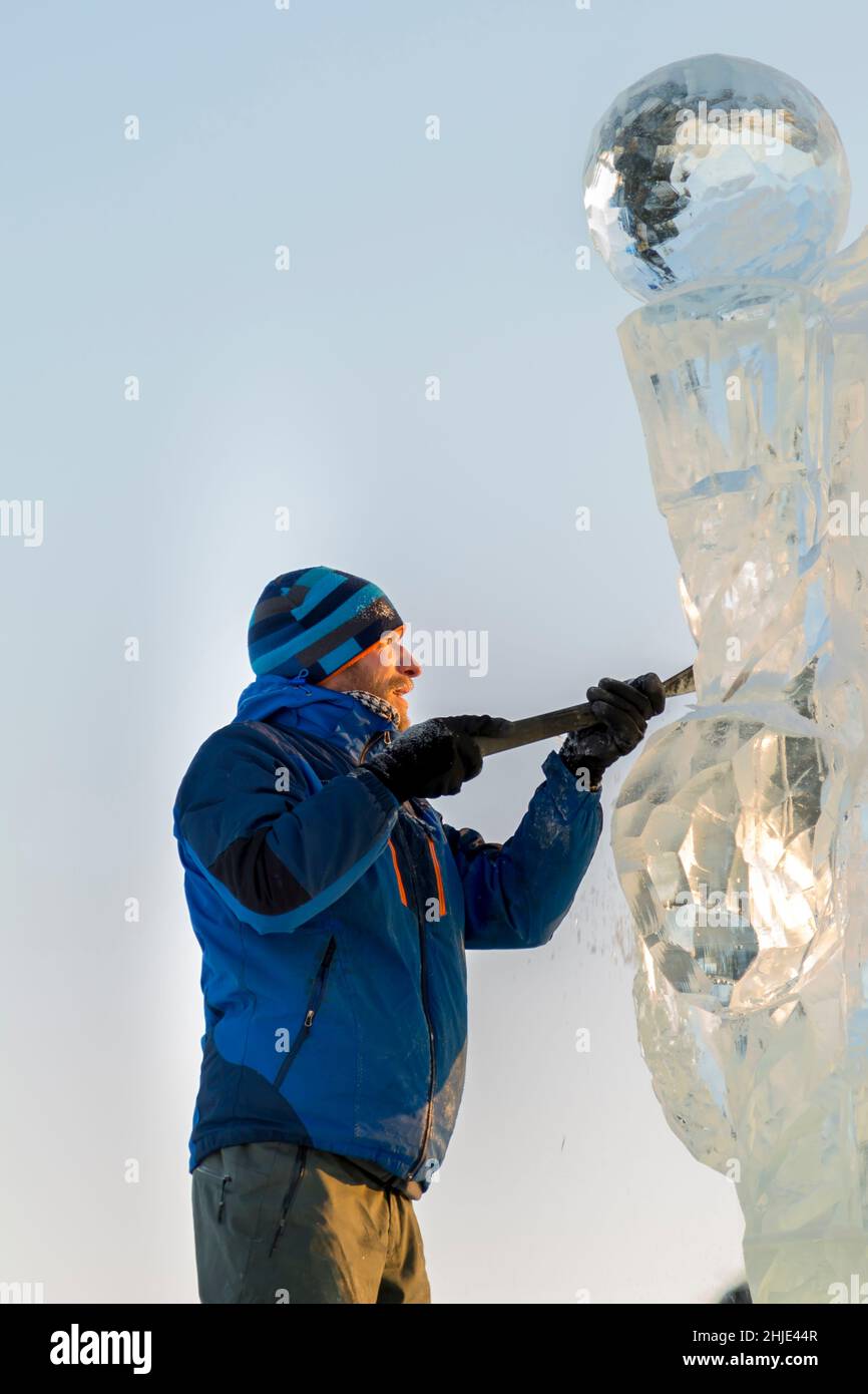 The sculptor cuts an ice figure out of a block of ice for Christmas ...