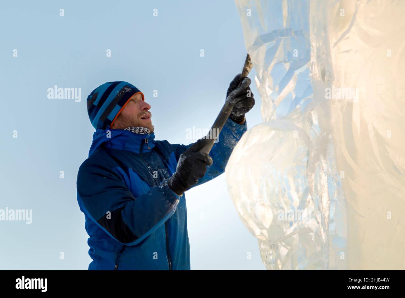 The sculptor cuts an ice figure out of ice with a chisel for Christmas ...
