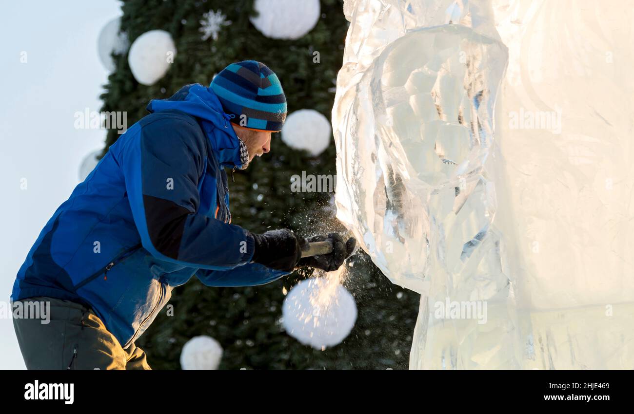 The sculptor cuts an ice figure out of a block of ice for Christmas ...