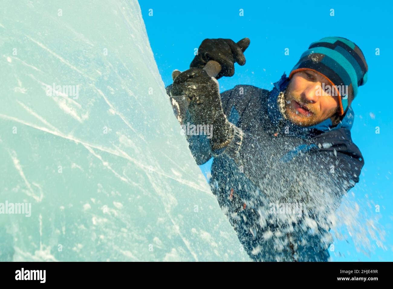 The sculptor cuts an ice figure out of ice with a chisel for Christmas ...