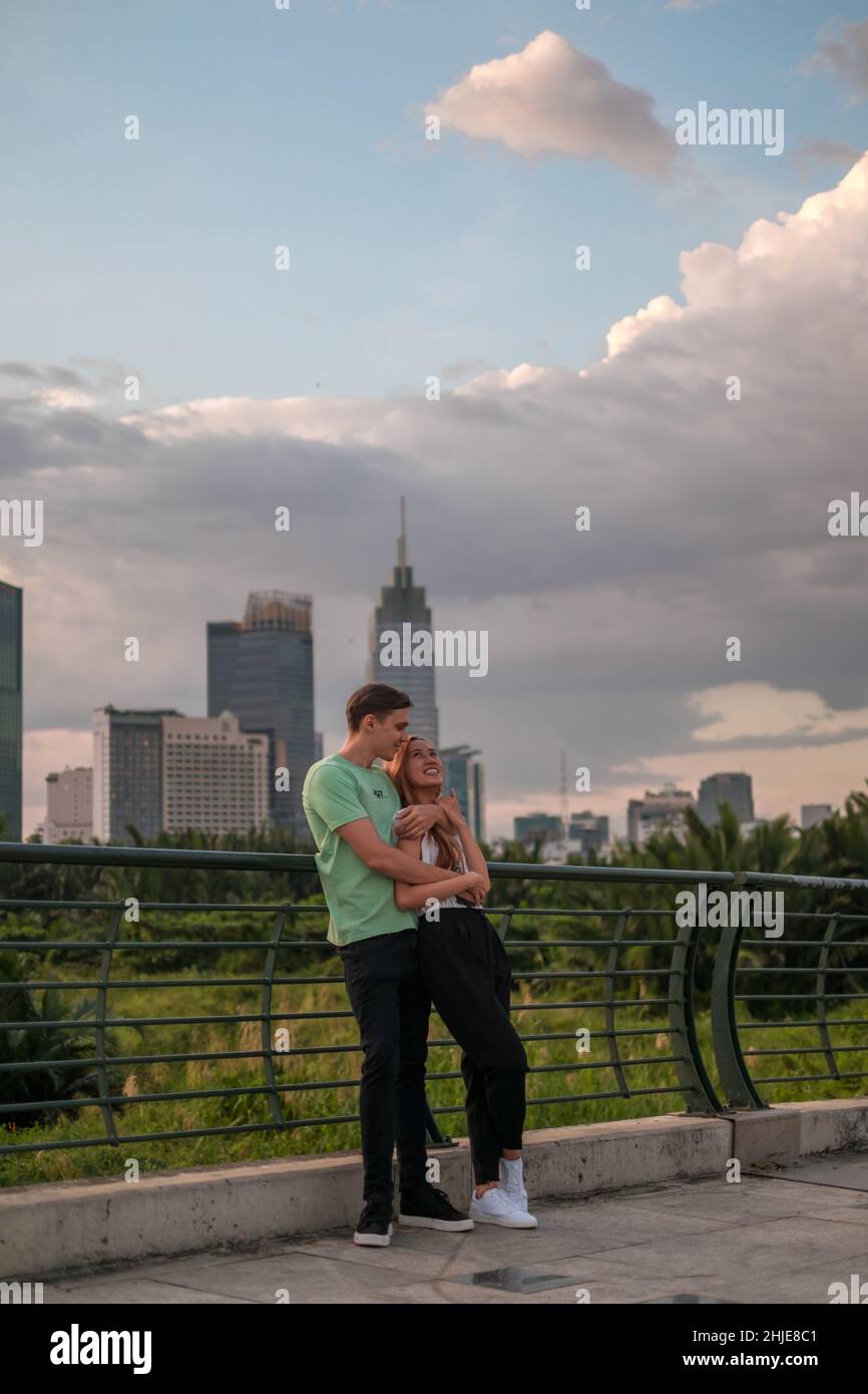 Lovely mixed couple standing on the bridge in the park in metropolis ...
