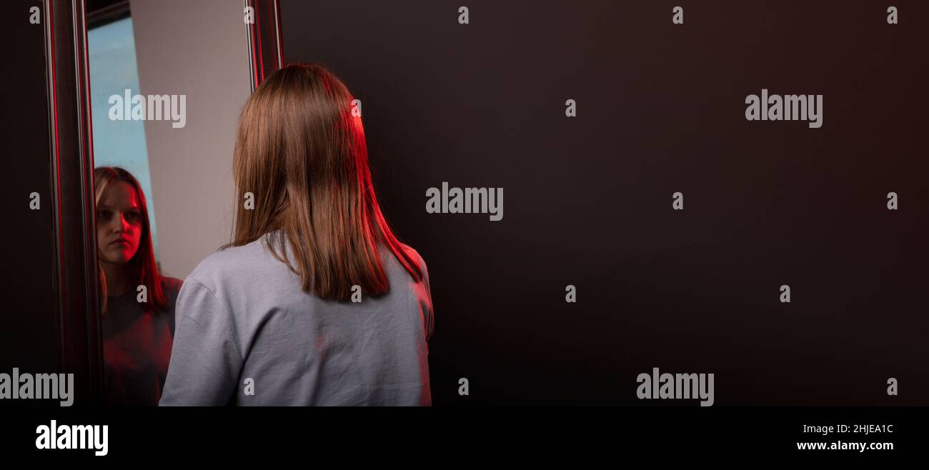 Young woman looking at her mirror reflection with grief. Unhappy sad ...