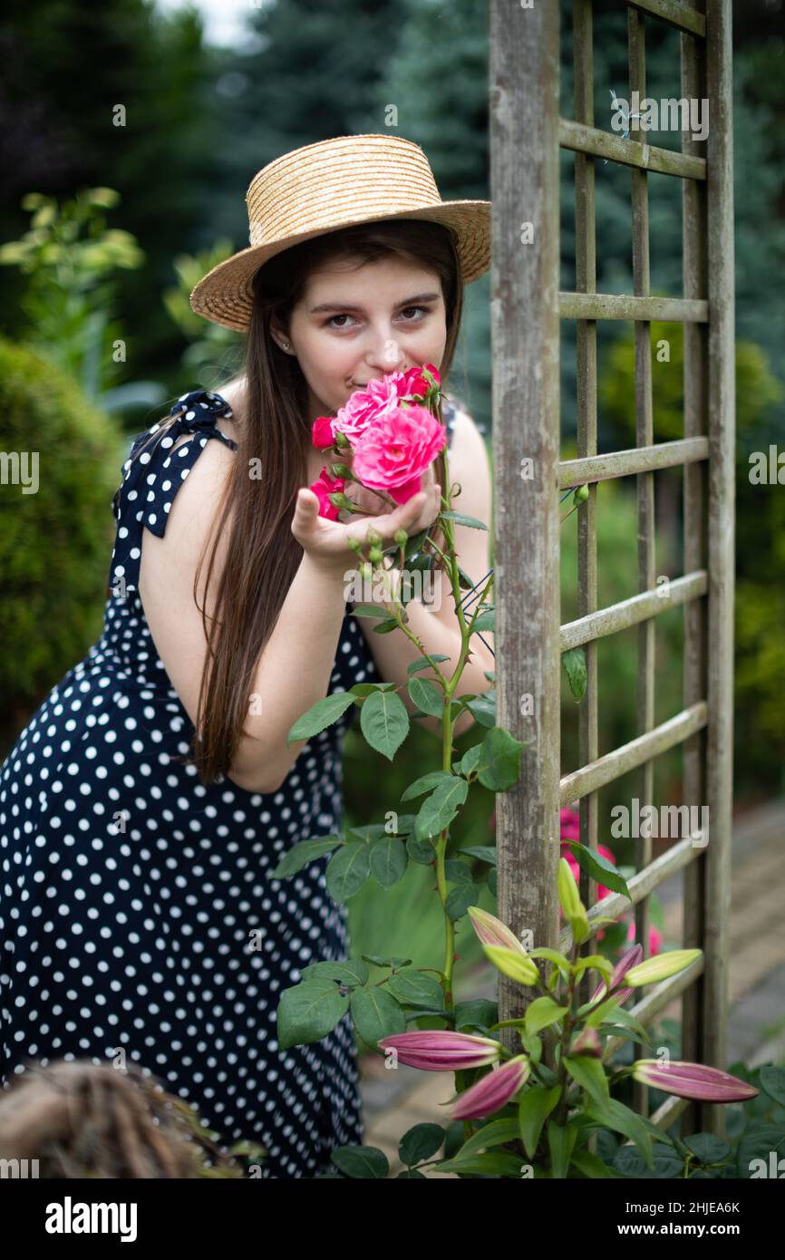 A young woman smells the pink roses in her garden Stock Photo - Alamy