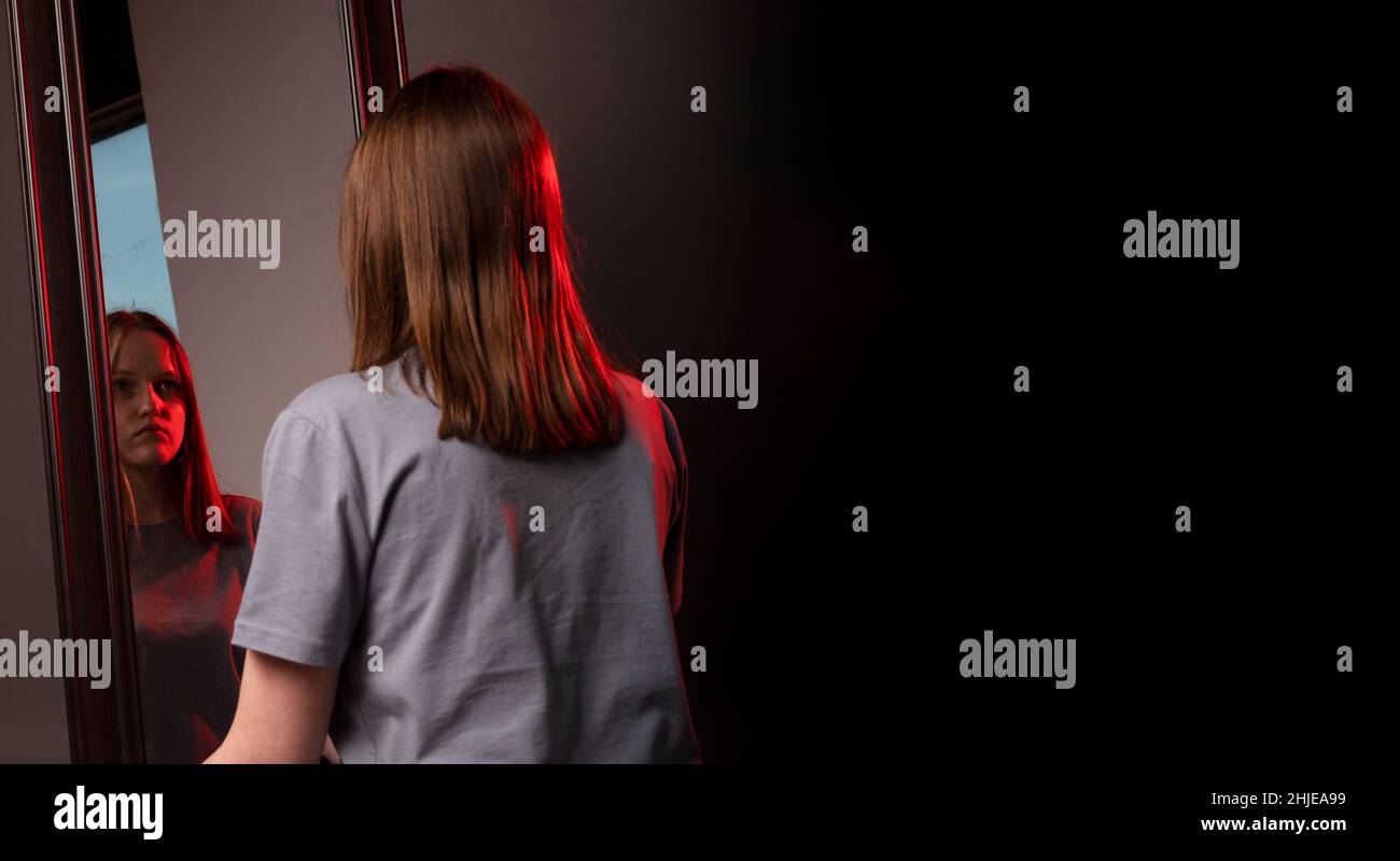 Young woman looking at her mirror reflection with grief. Unhappy sad ...