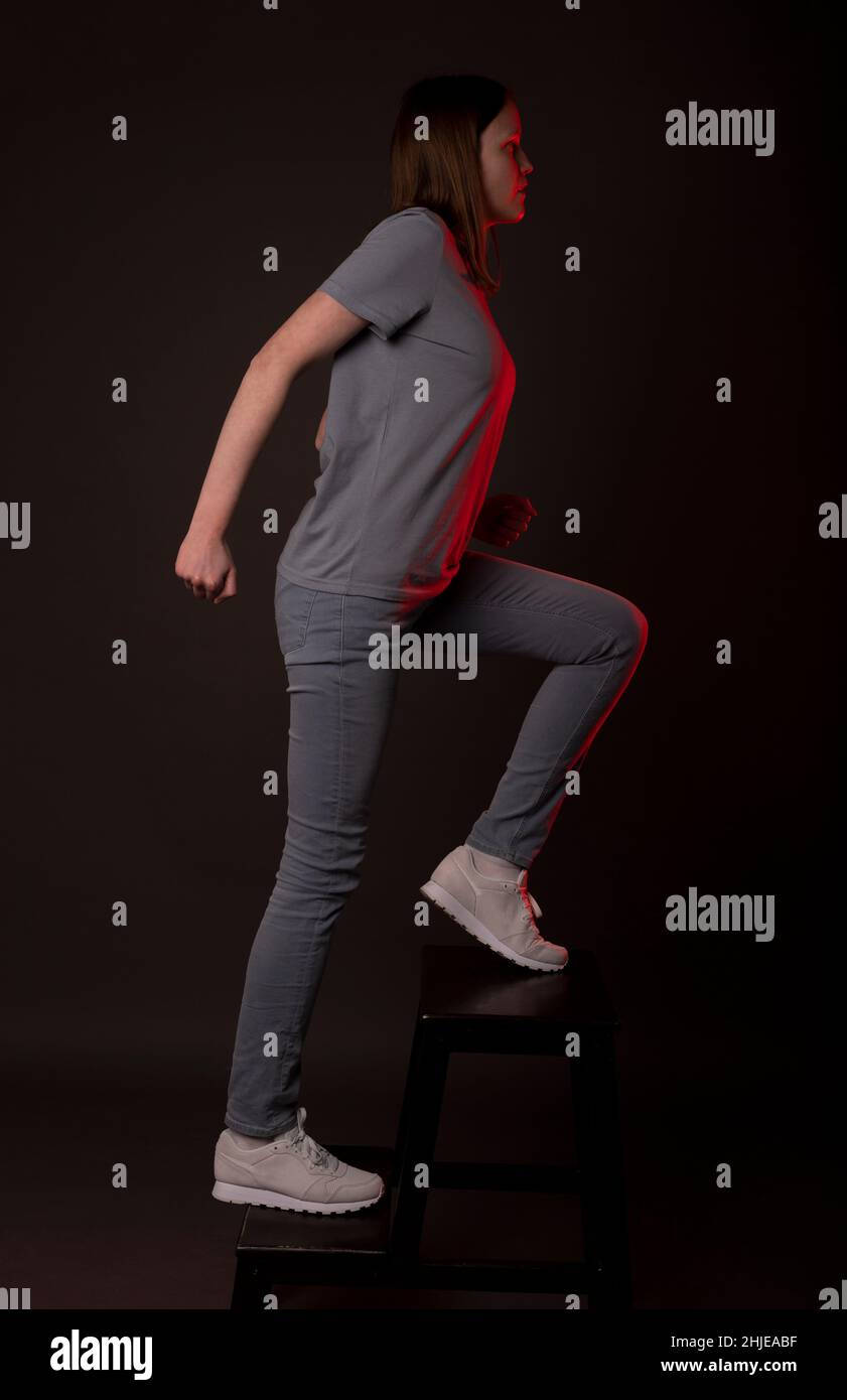 Young woman walking up stairs, running upstairs on black background ...