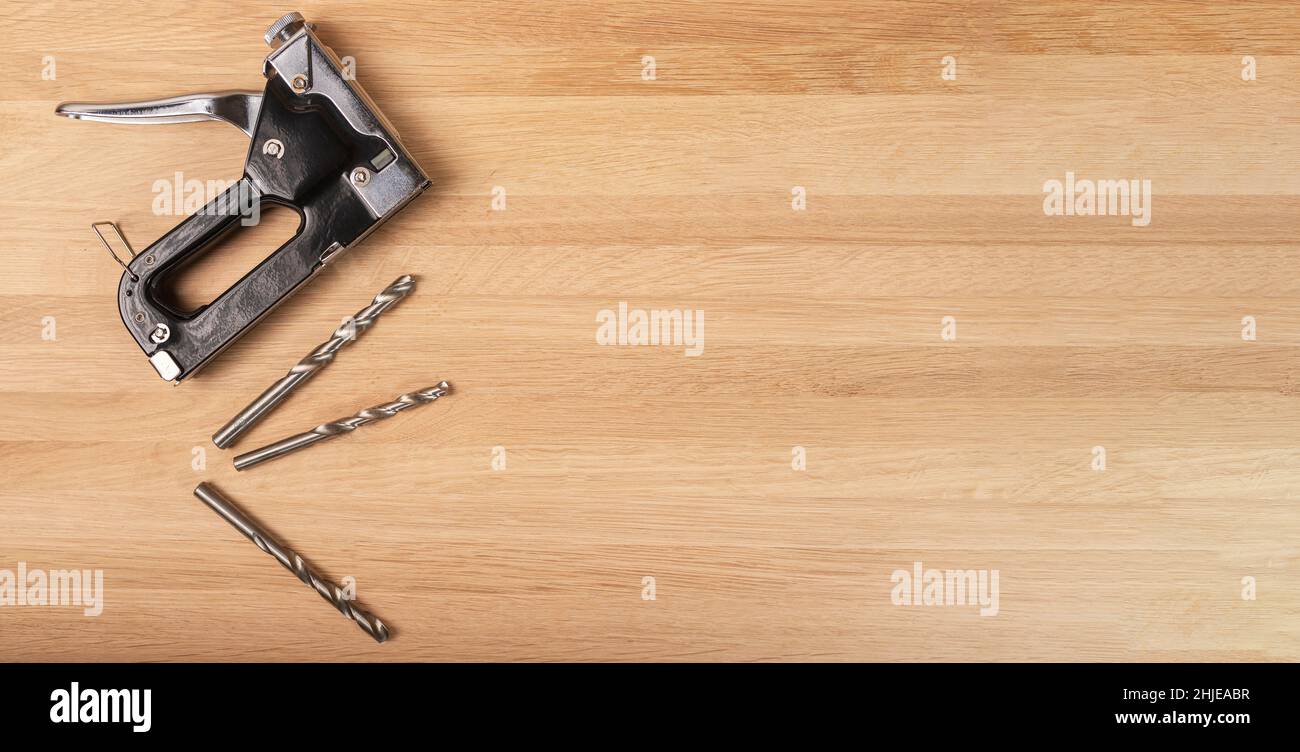 Construction stapler with metal steel drills on wooden background, flat ...